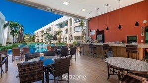 Uma área de piscina ao ar livre com assentos e um bar, cercada por edifícios.