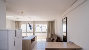 Uma sala de estar moderna e bem iluminada, com um sofá, uma mesa de madeira e uma TV fixada na parede.