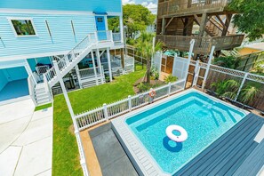 Uma casa de dois andares com piscina, deck de madeira e quintal cercado.