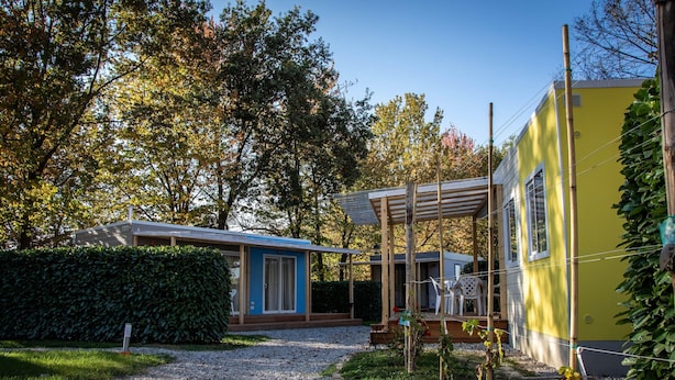 Uma área residencial com um edifício amarelo, uma estrutura azul e um espaço de estar coberto ao ar livre.
