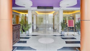Um saguão de hotel com entrada de vidro, um design circular no chão e teto roxo.