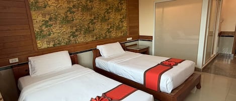 Quarto de hotel com duas camas, cabeceira de madeira, um mapa na parede e uma porta deslizante.