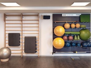 Uma academia com equipamentos de ginástica, incluindo barra de puxar, bolas de medicina e um tapete de yoga.