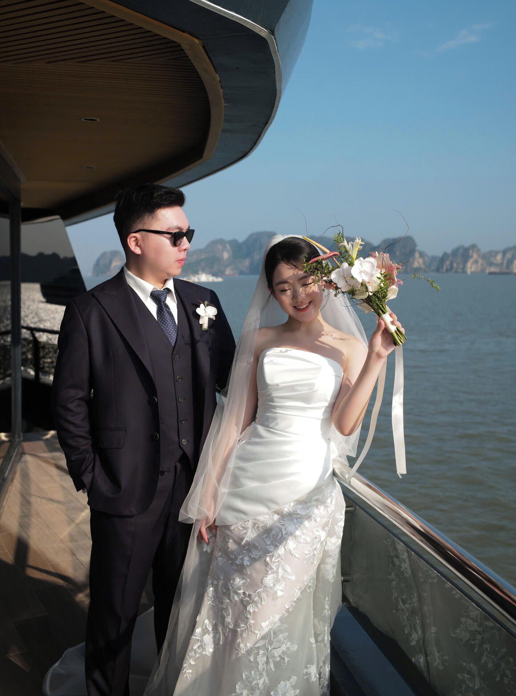 Um casal em um barco, com vista para a água e terra ao longe.