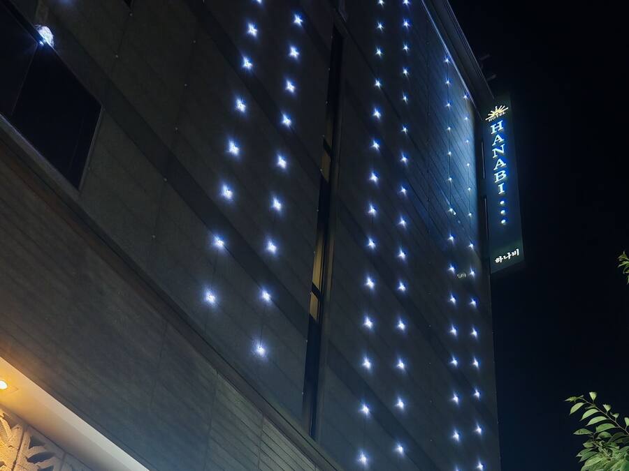 Fachada de hotel com letreiros iluminados e desenhos decorativos.