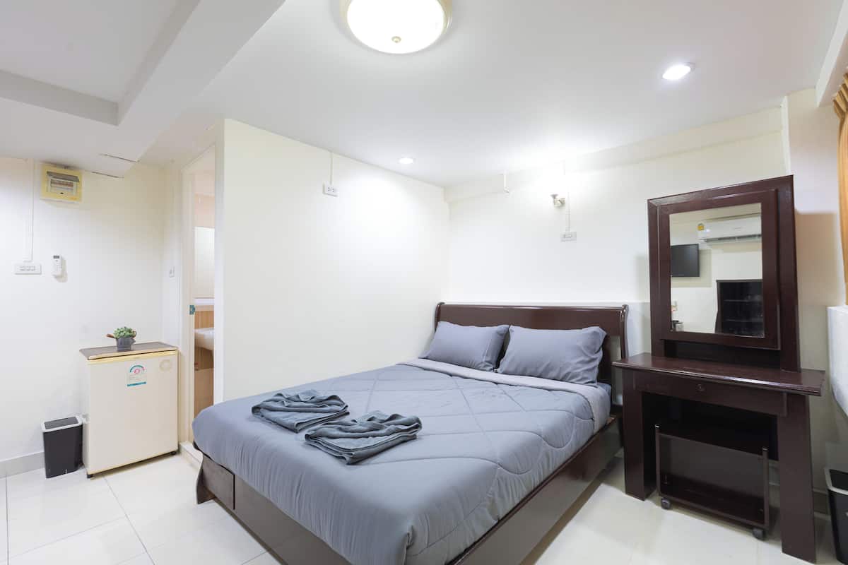 Quarto com cama, cômoda, espelho e um pequeno armário.