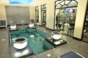 Uma área de spa com piscina, equipamentos de ginástica e cadeiras para relaxamento.