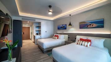 Quarto de hotel moderno com duas camas, uma escrivaninha, um vaso com flores e um quadro na parede.