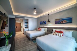 Quarto de hotel moderno com duas camas, uma escrivaninha, um vaso com flores e um quadro na parede.
