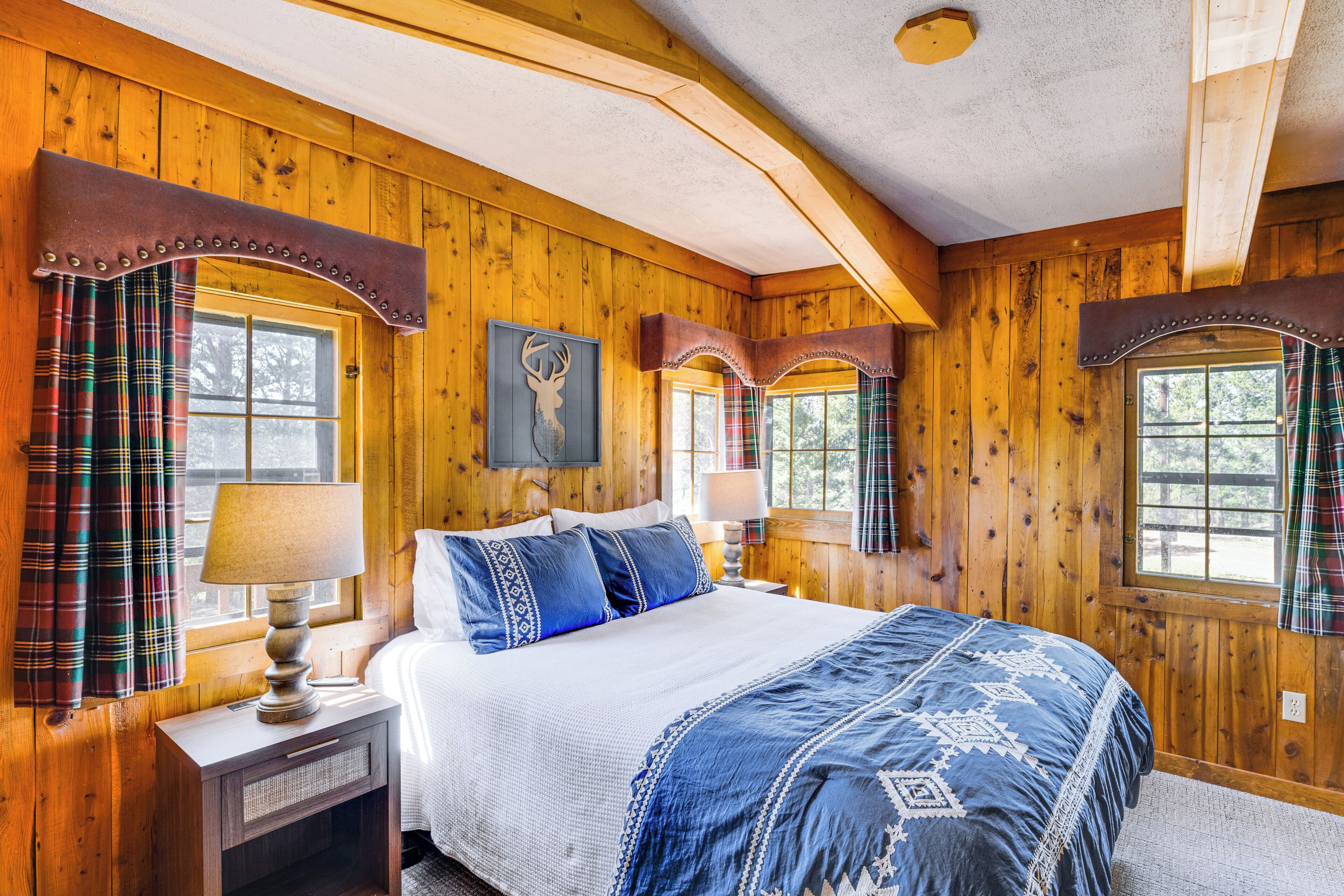 Quarto de cabana de madeira com cama, cortinas e abajur.