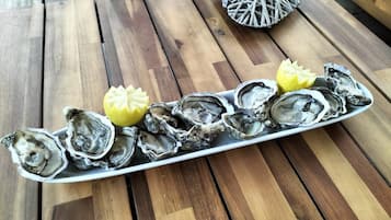 Uma mesa de madeira com uma travessa de ostras e gomos de limão.