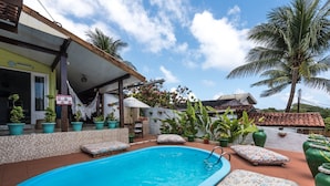 Piscina com espreguiçadeiras e plantas em vasos.