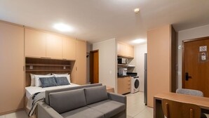 Um espaço compacto com cama, sofá, cozinha compacta e área de refeições.