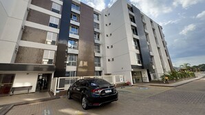 Edifício com vários andares e área de estacionamento em frente.