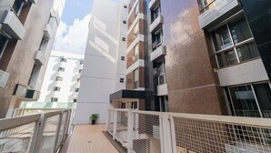 Um edifício residencial de vários andares com varandas, fachada em azulejos e céu limpo.