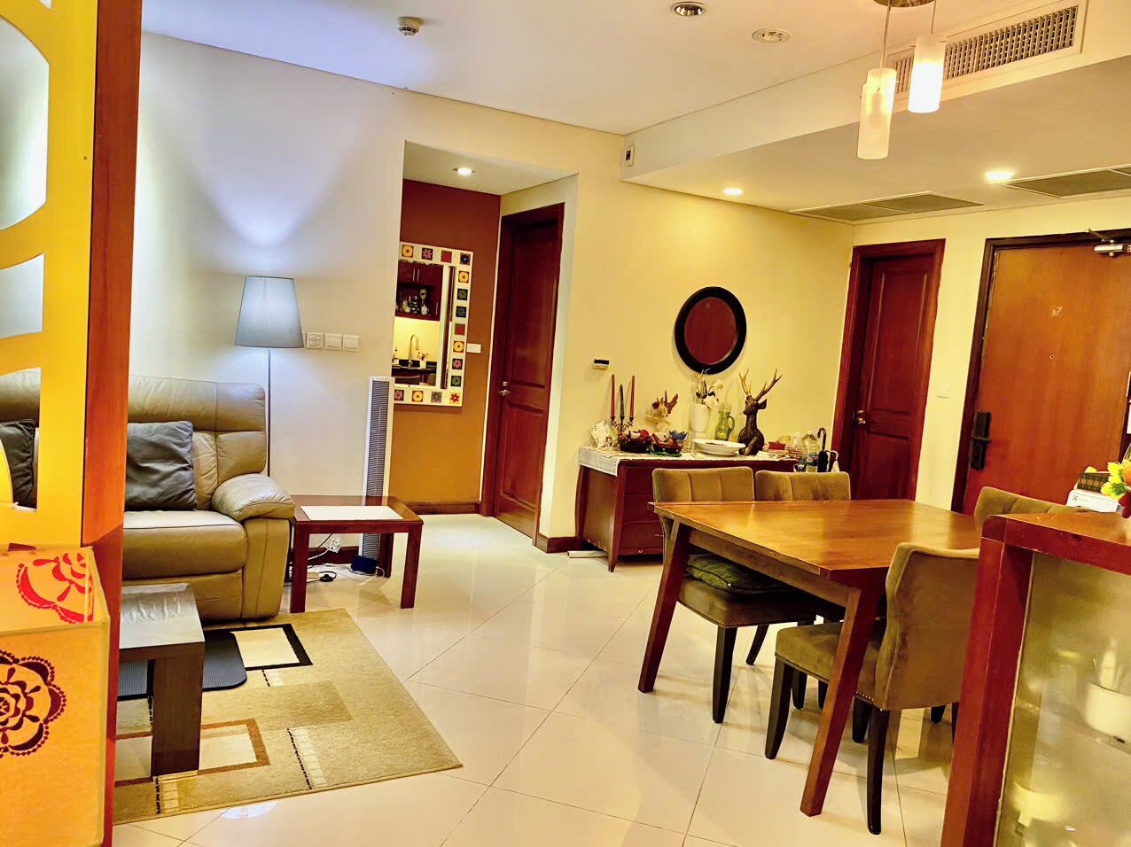 Uma sala de estar moderna com sofá, mesa de centro e área de jantar com mesa e cadeiras de madeira.