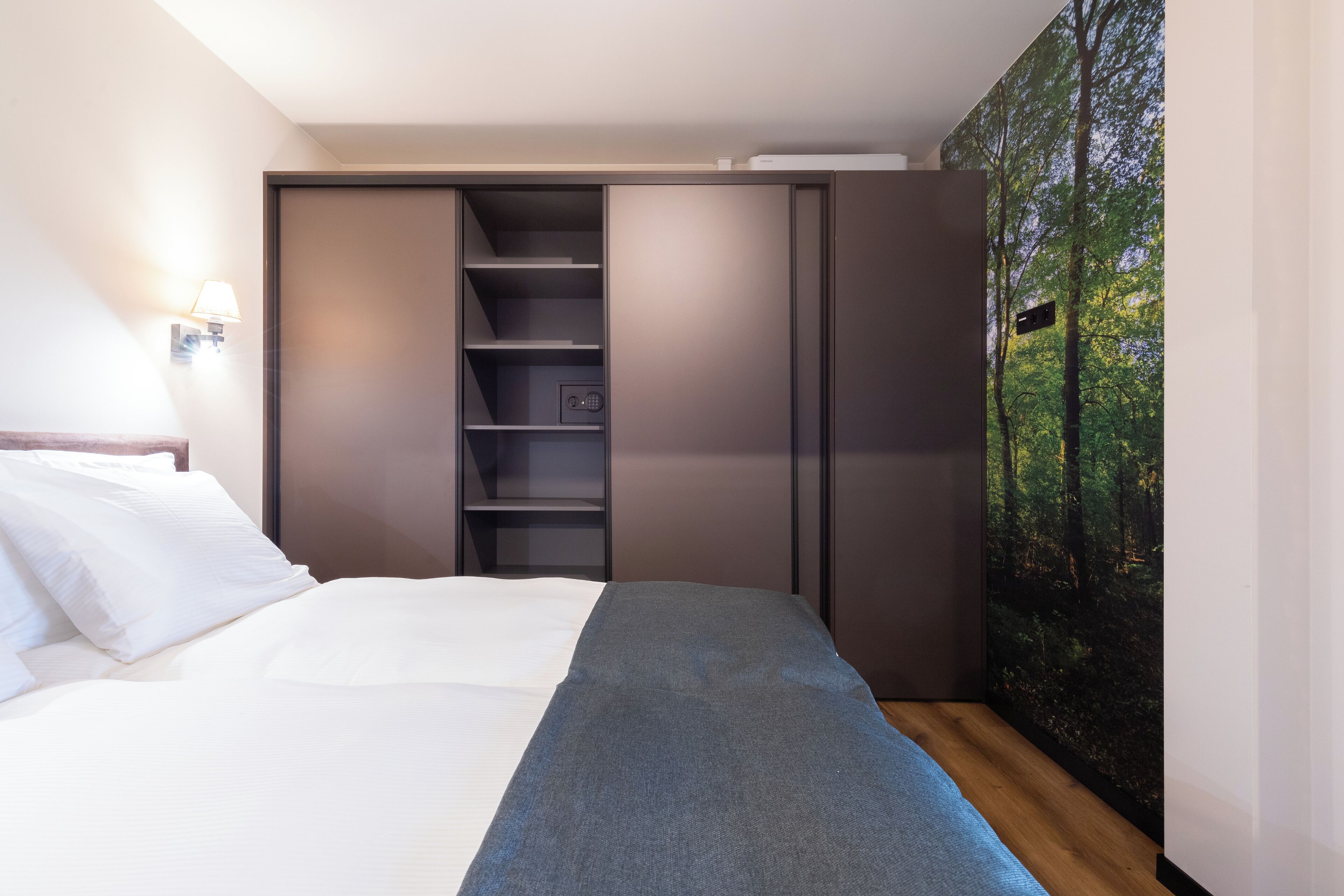 Quarto com cama, guarda-roupa e um mural na parede retratando uma floresta.