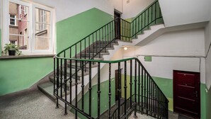 Uma escadaria com paredes verdes e uma porta vermelha, que dá acesso a um andar superior.