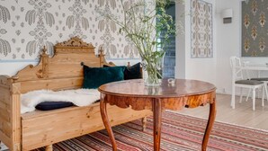 Um quarto com sofá de madeira, mesa redonda de madeira e papel de parede estampado.