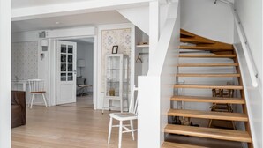 Um interior moderno com escada de madeira, área de jantar com uma cadeira branca e cozinha com armário branco.