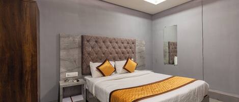 Quarto moderno com uma cama grande, uma mesinha de cabeceira, um guarda-roupa e um espelho na parede.