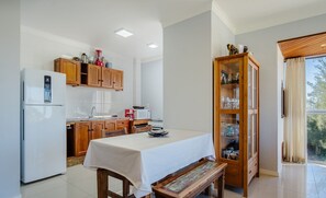Uma cozinha moderna com armários de madeira, uma geladeira branca, uma mesa de jantar com um banco e um armário com portas de vidro.