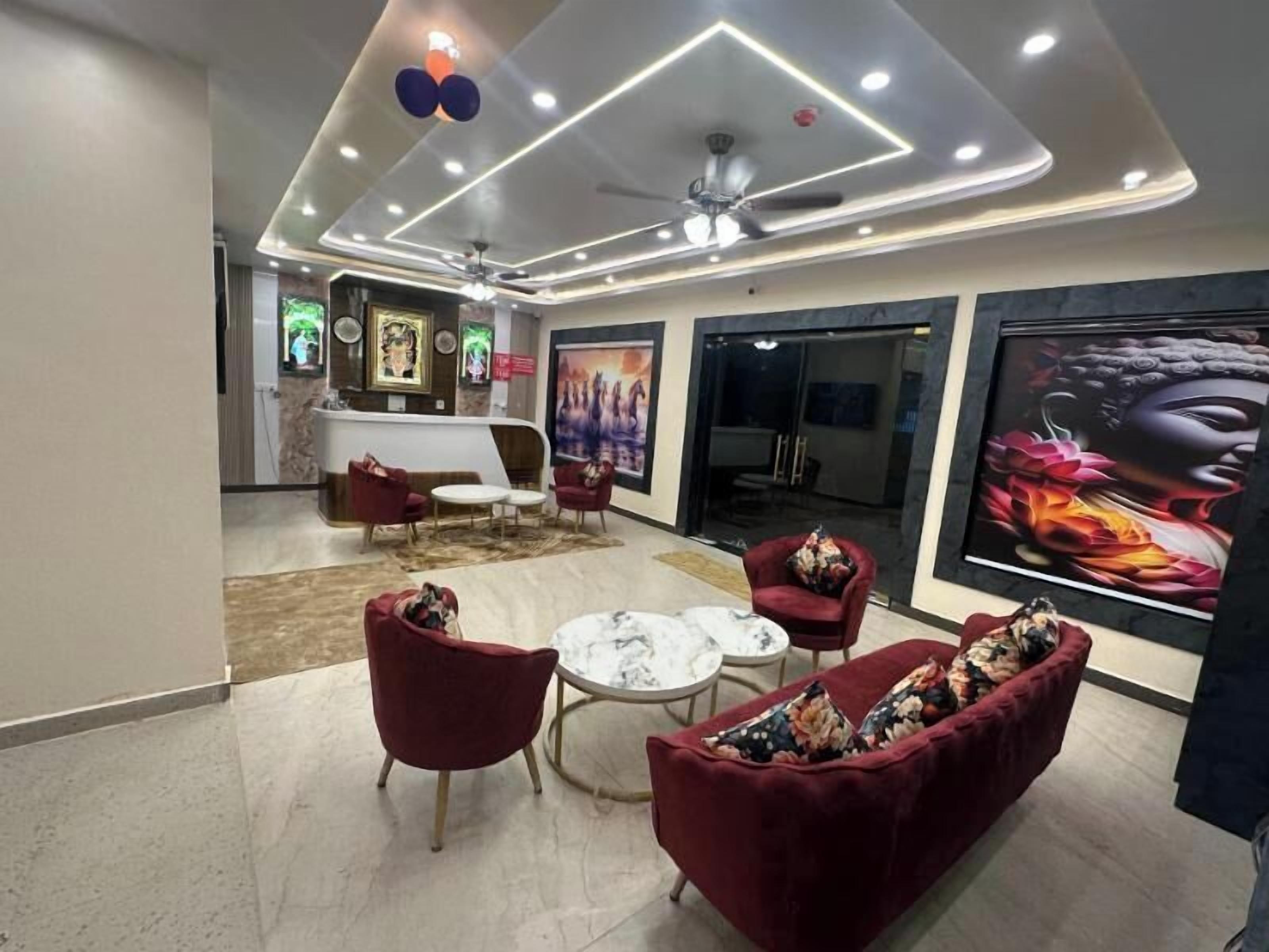 Uma sala de estar moderna com um sofá vermelho, uma mesa de centro e um ventilador de teto. Ao fundo, uma área de recepção com balcão e cadeiras.