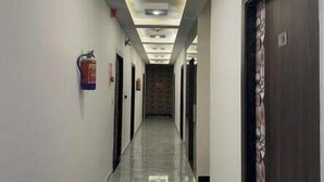 Um corredor comprido e estreito com piso de mármore polido e iluminação embutida.