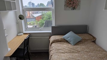 Quarto com cama, escrivaninha e radiador.