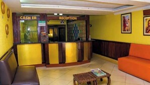 Uma área de recepção com balcão de caixa, mesa de recepção e um sofá.