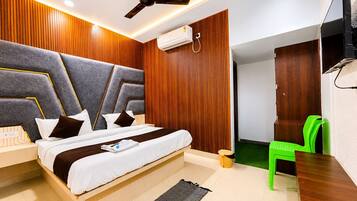 Quarto moderno com cama, ventilador de teto, ar condicionado, uma cadeira verde e guarda-roupa de madeira.