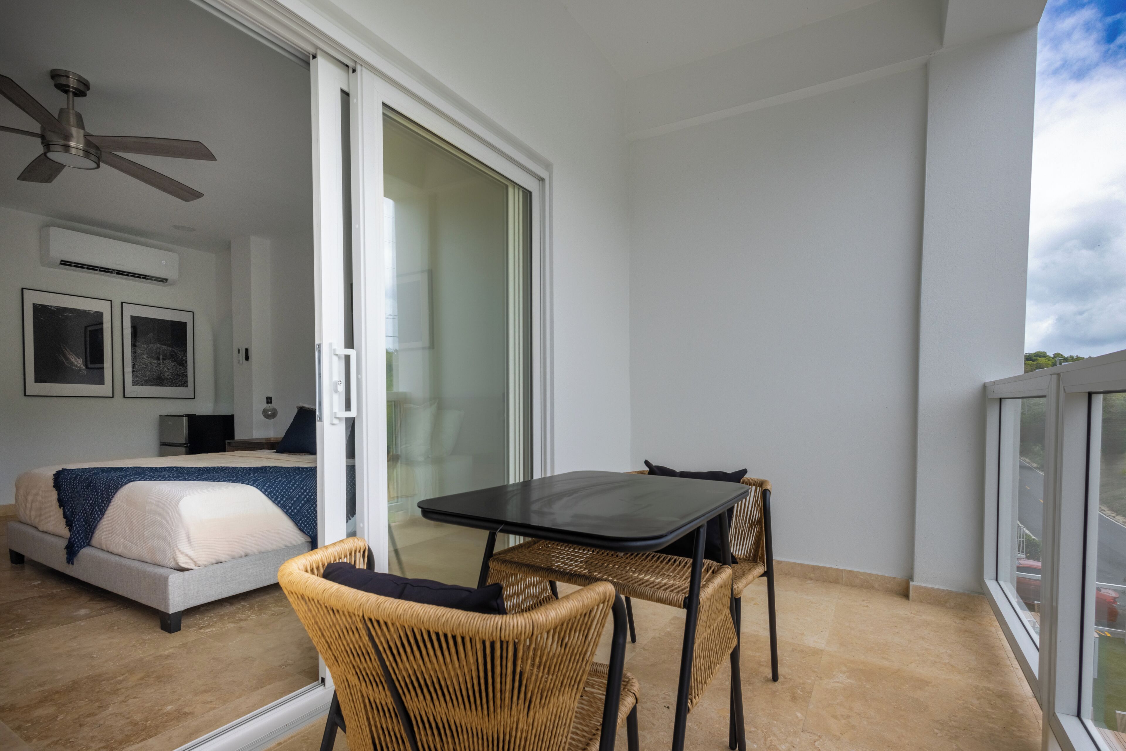 Uma varanda com cama, mesa e cadeiras de vime.