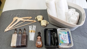 Um conjunto de artigos de higiene pessoal organizados e uma cesta com toalhas sobre a cama.