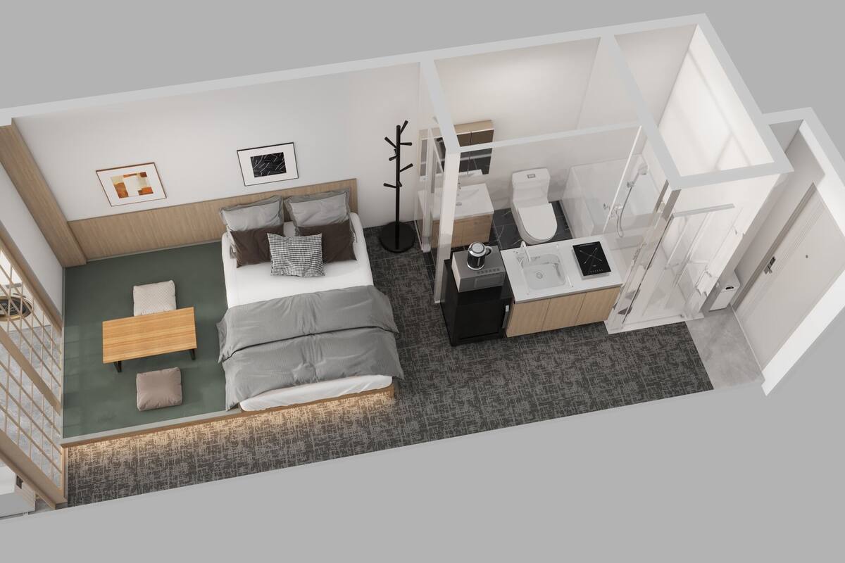Quarto de hotel compacto com cama, mesa de cabeceira e um pequeno espaço de estar.
