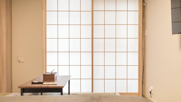 Um quarto japonês tradicional com tatames, uma mesa de madeira baixa e uma porta de papel shoji.