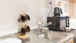 Cozinha com uma pia de aço inoxidável, chaleira e máquina de café.
