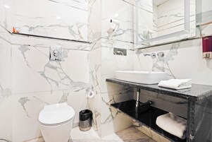 Casa de banho com sanita branca, lavatório preto e espelho sobre o lavatório.