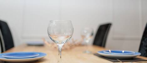 Uma mesa de jantar com uma taça de vinho de vidro transparente, pratos azuis e um garfo.