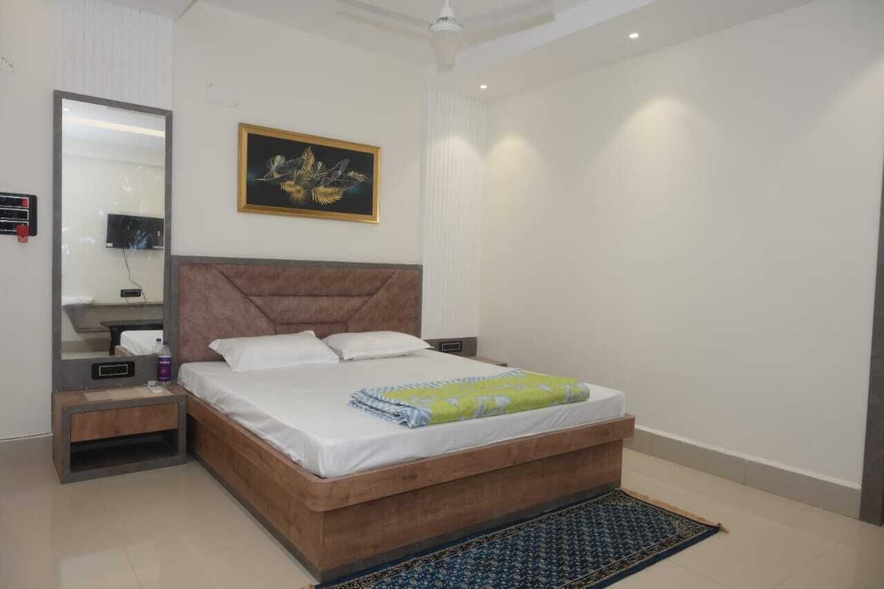 Quarto moderno com uma cama grande, uma mesa de cabeceira, um espelho e uma TV fixada na parede.