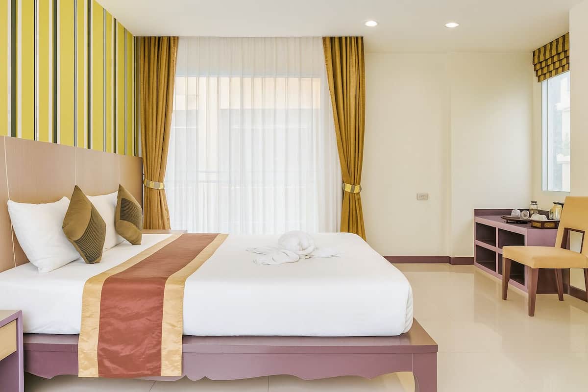 Quarto de hotel com cama, escrivaninha e cadeira.