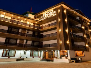Um edifício de vários andares com sacadas, uma placa com a inscrição 'ECKO PREMIER NEW YORK' e uma entrada bem iluminada.