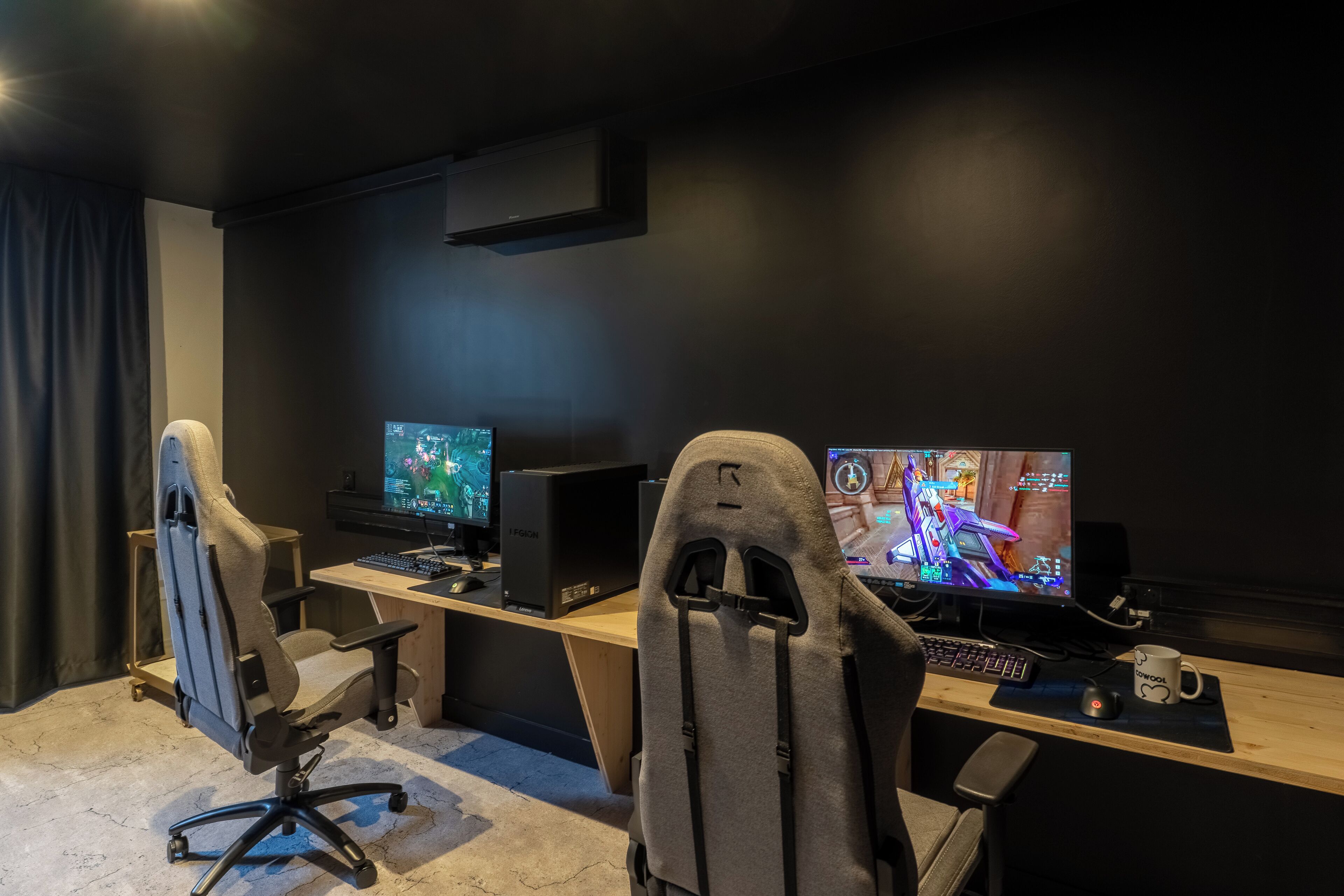 Uma configuração de jogos com dois monitores, um teclado e um rato sobre uma mesa de madeira.