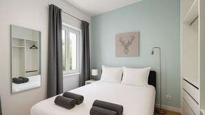 Um quarto moderno com uma cama grande, uma mesa de cabeceira, uma luminária, um espelho e uma obra de arte na parede.