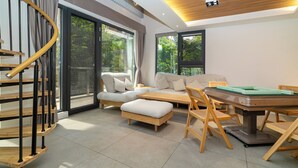 Uma sala de estar moderna com escada de madeira, um conjunto de sofá, uma mesa de centro e uma mesa de bilhar.