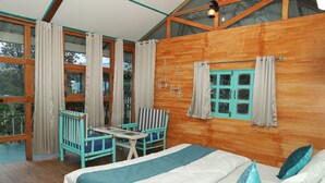 Uma cabana de madeira com uma cama, uma mesa e uma cadeira.
