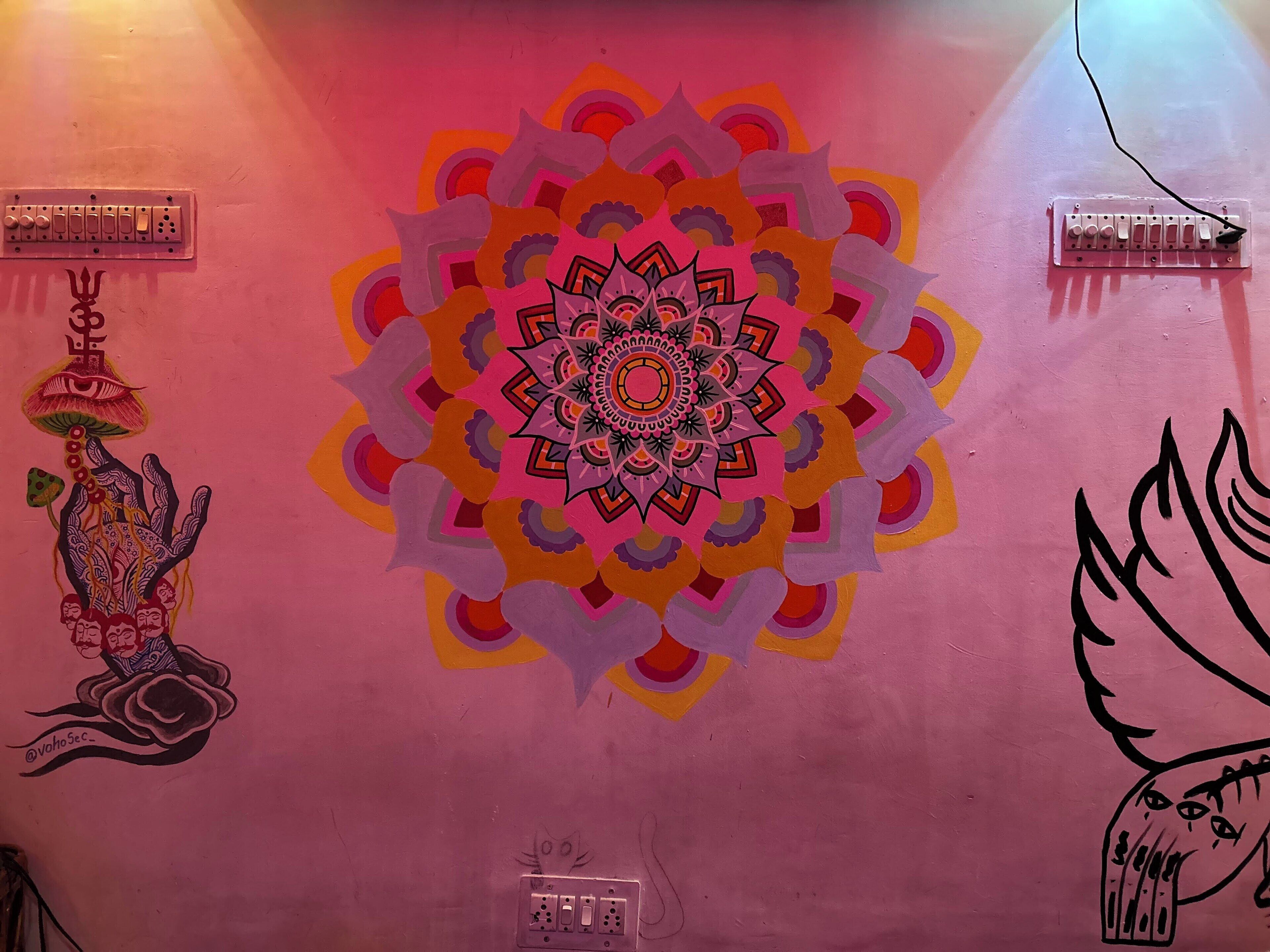 Paredes com um grande desenho de mandala, tomadas e um filtro de energia.