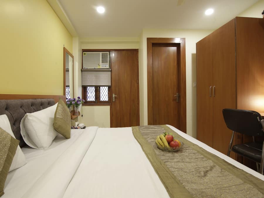 Quarto de hotel com cama, escrivaninha e guarda-roupa.