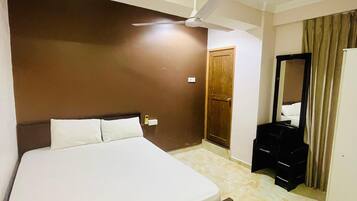 Quarto de hotel com uma cama grande, um ventilador de teto, um guarda-roupa e um espelho.