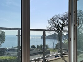 Vista da janela com vista para um corpo d'água, uma ponte e uma árvore.