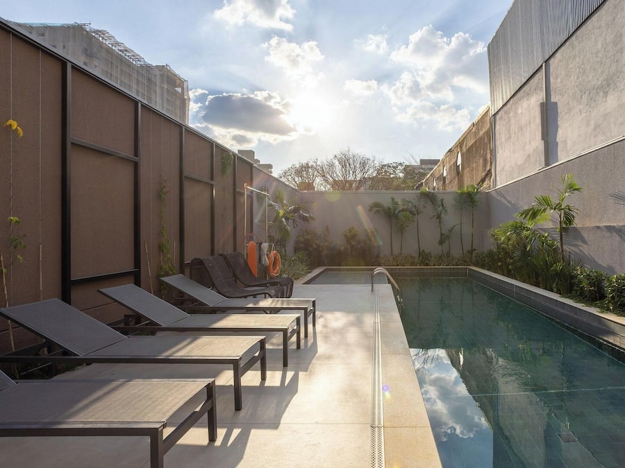 Área de piscina com espreguiçadeiras e piscina transparente.